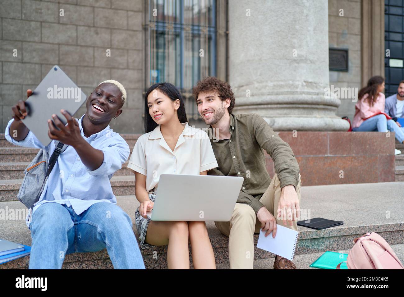 student showing his friends a photo on a digital tablet. technology ...