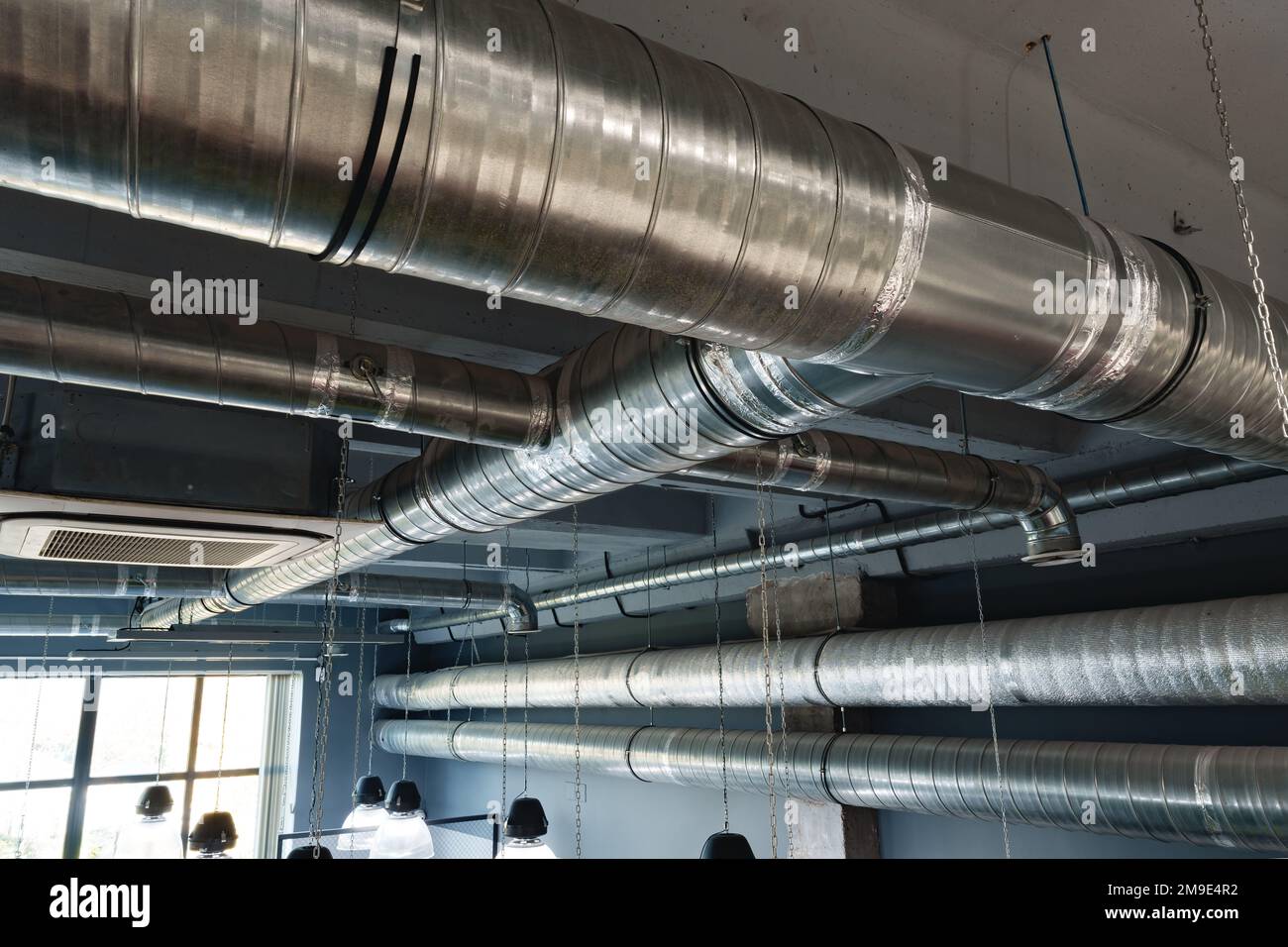 Silver ventilation pipes hanging from the ceiling inside the building ...