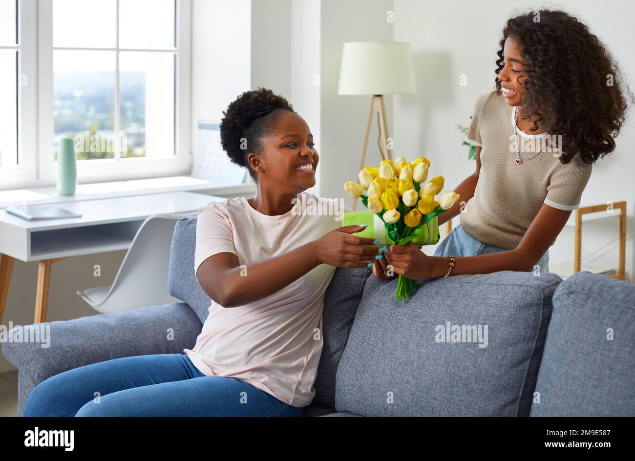 Happy, smiling child gives gives bouquet of beautiful flowers to mom on ...