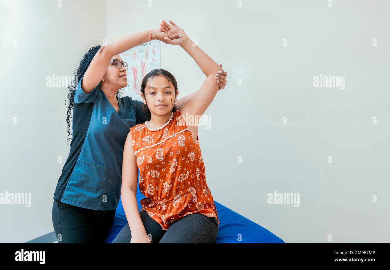 Young physiotherapist with patient rehabilitating shoulder and elbow ...