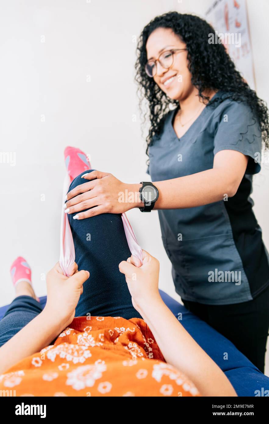 Knee rehabilitation physiotherapy with resistance band. Physiotherapist ...