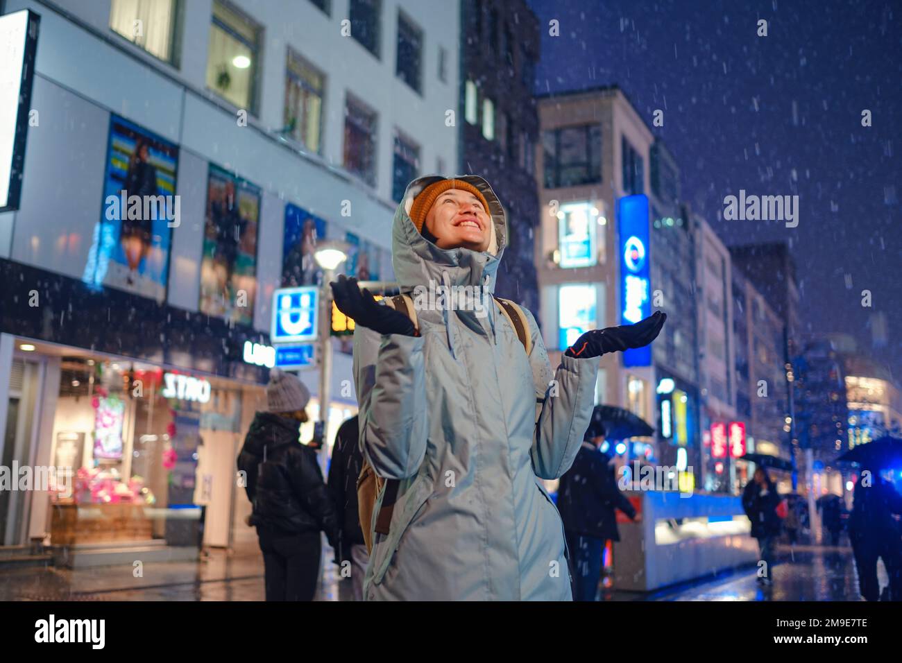 snowfall woman in a blue jacket and yellow hat christmas outside, city ...