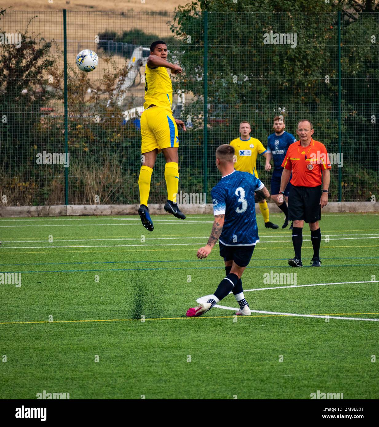 A soccer player in yellow kit blocking the free kick of his competitor ...