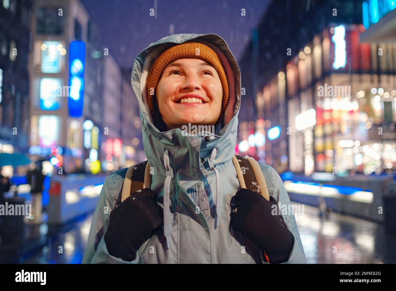 snowfall woman in a blue jacket and yellow hat christmas outside, city ...