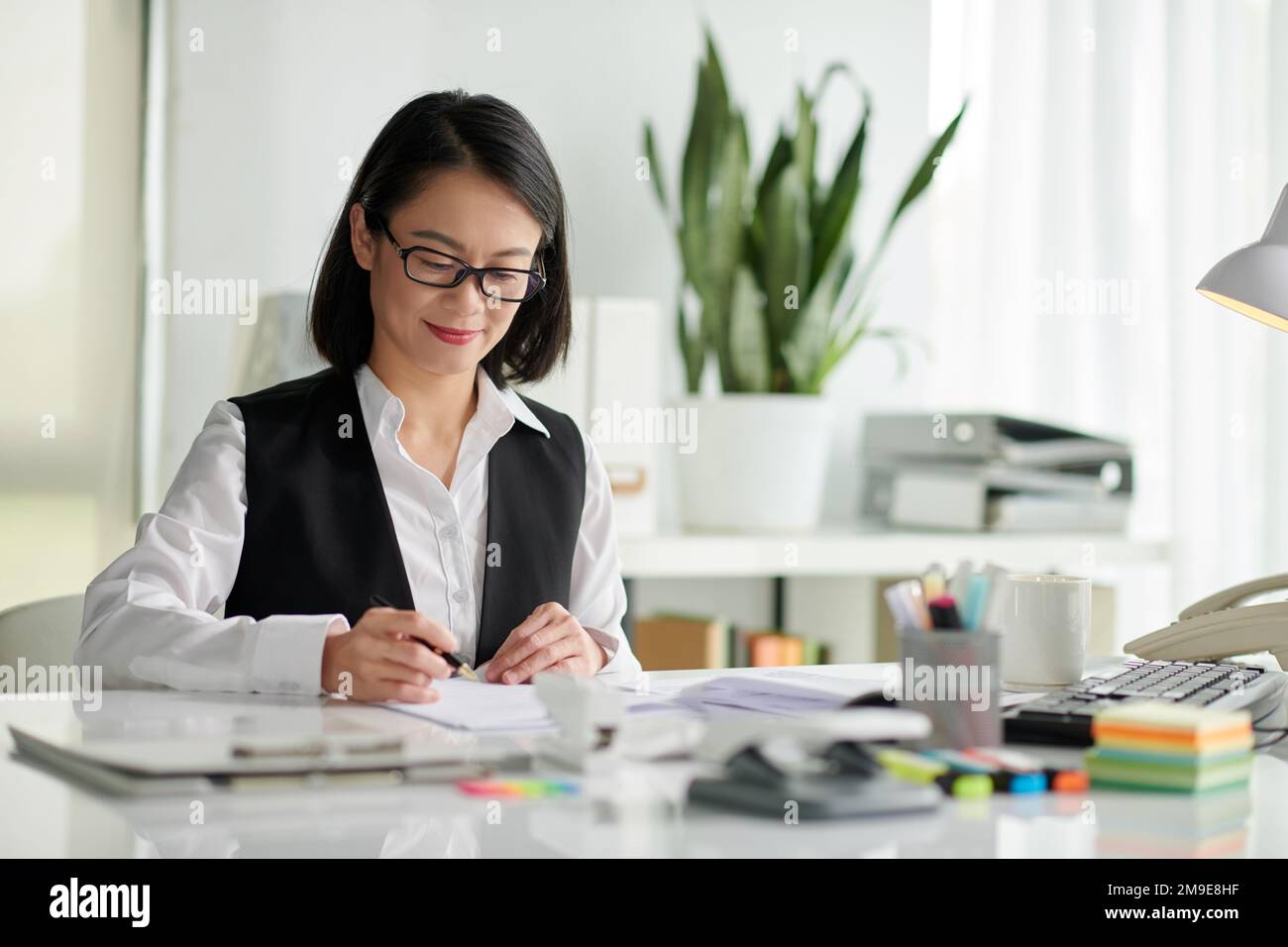 Smiling social worker checking documents of client Stock Photo - Alamy