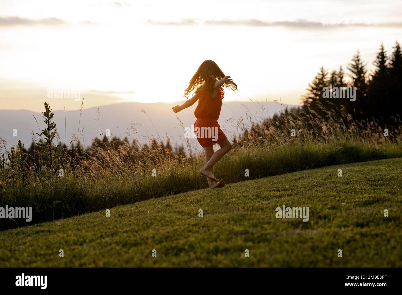 Girl, 8 years, moving in a meadow at sunset, Carinthia, Austria Stock ...