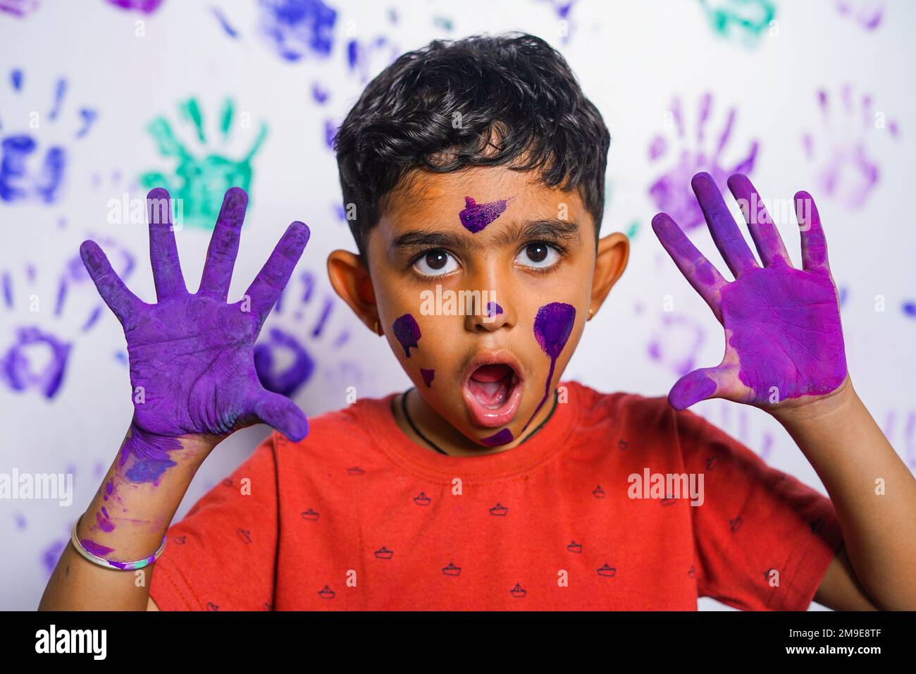 grimacing Cheerful kid showing painted hands by looking camera at home ...