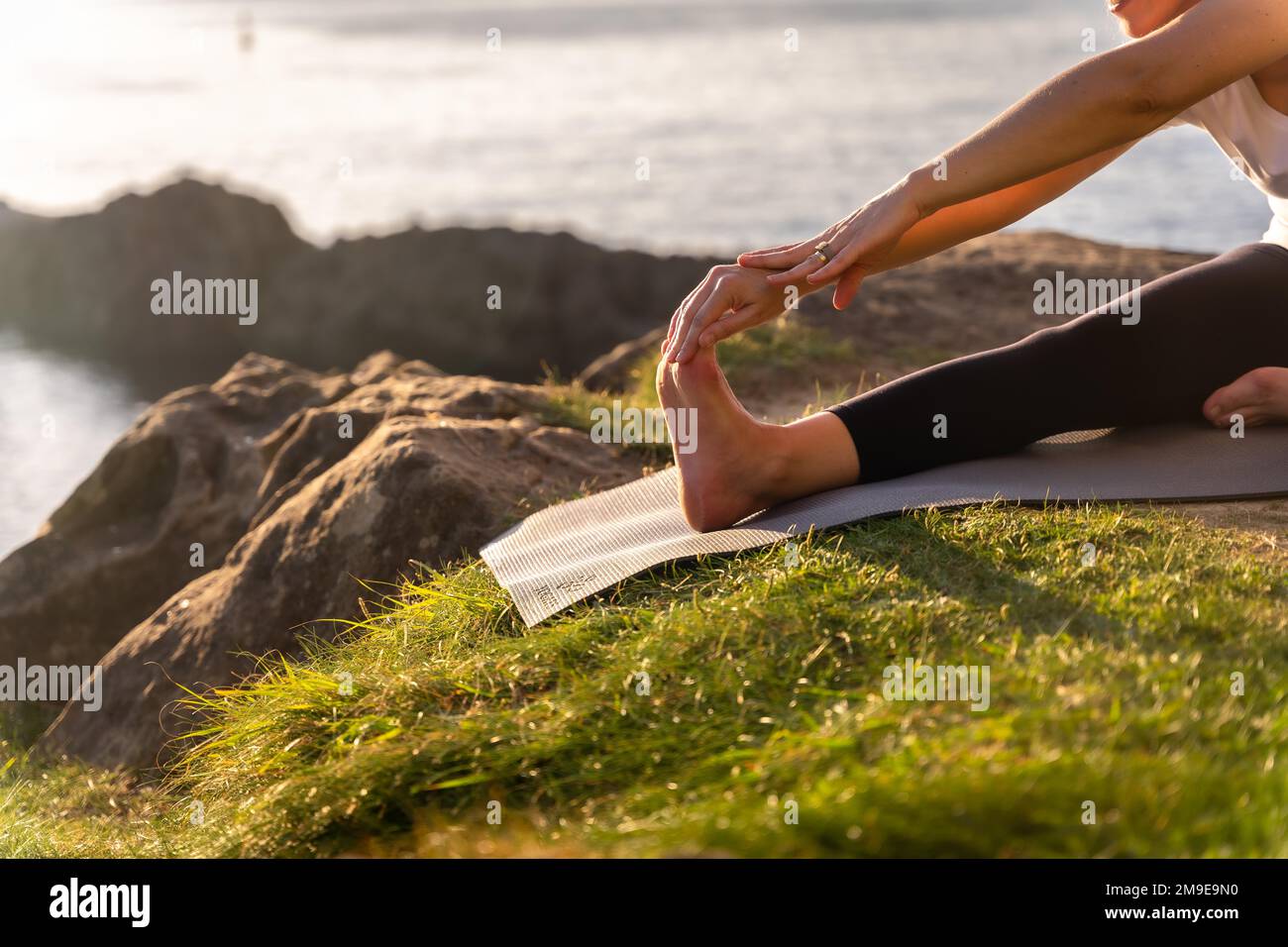Feet of a woman doing yoga exercises in nature by the sea, stretching ...