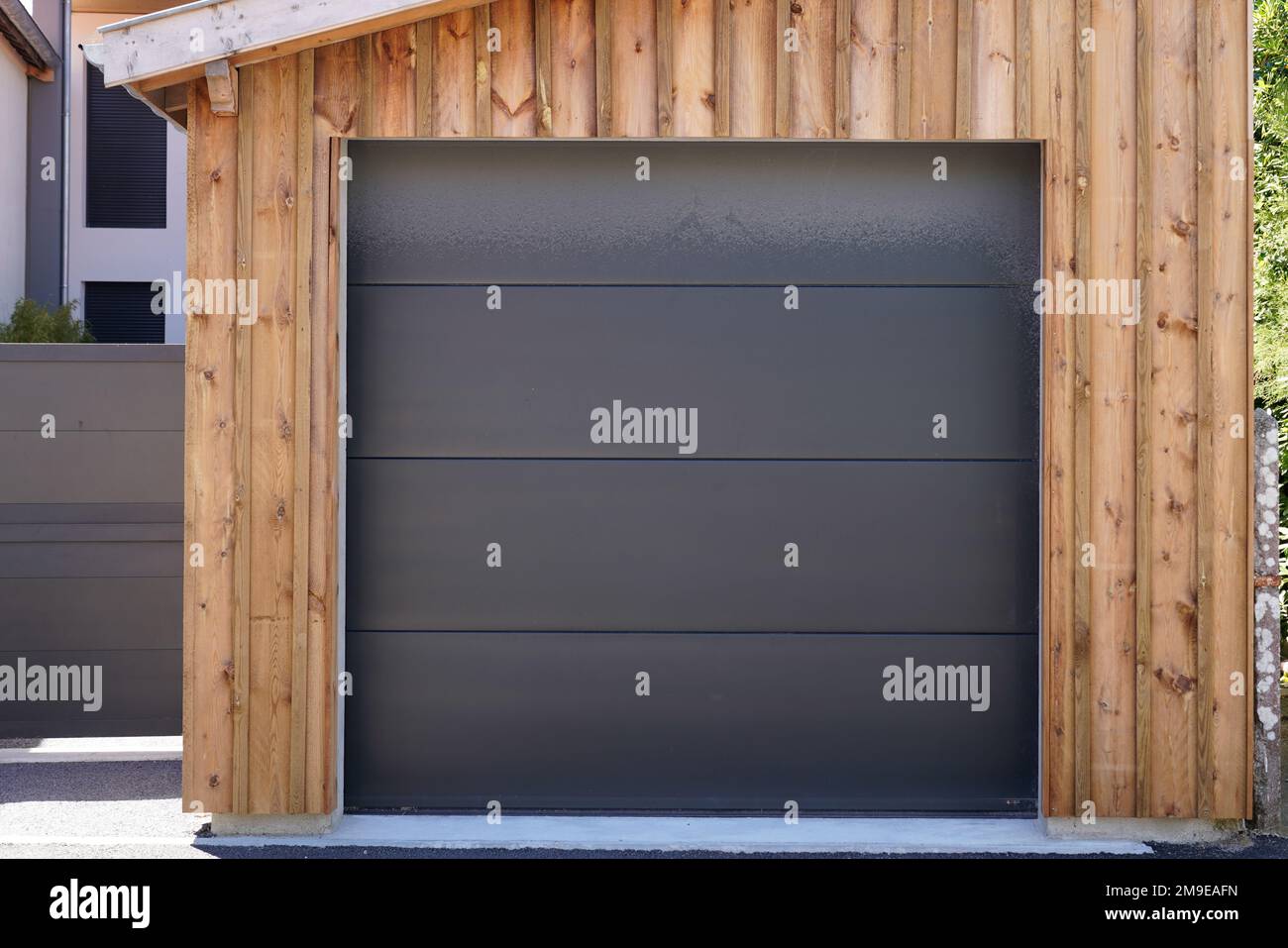 Modern car garage sectional door in dark grey of wooden building house ...