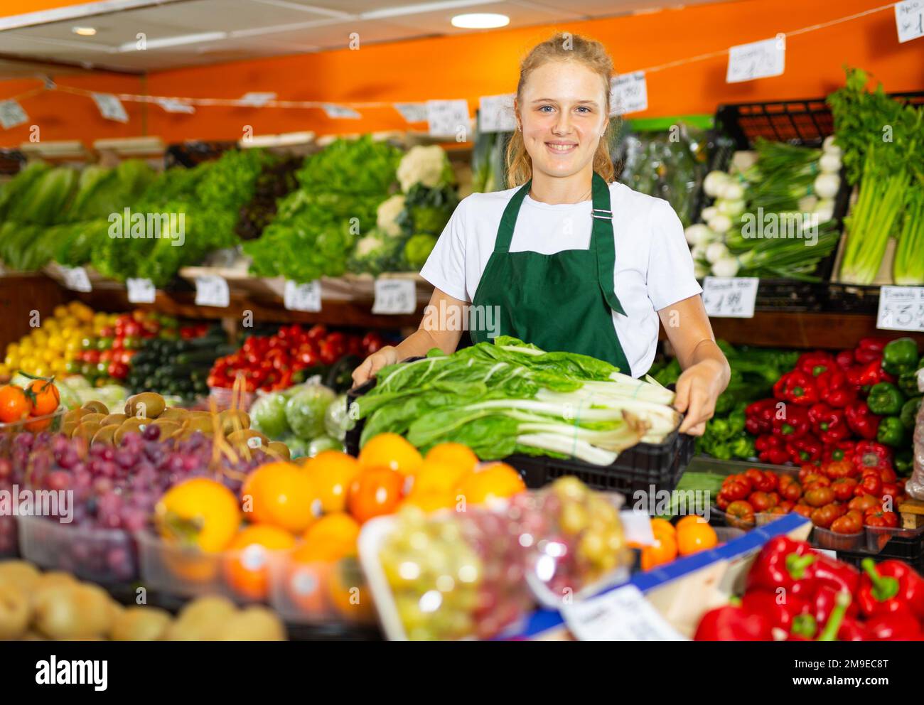Teenage girl in uniform posing with salad in grocery shop Stock Photo ...