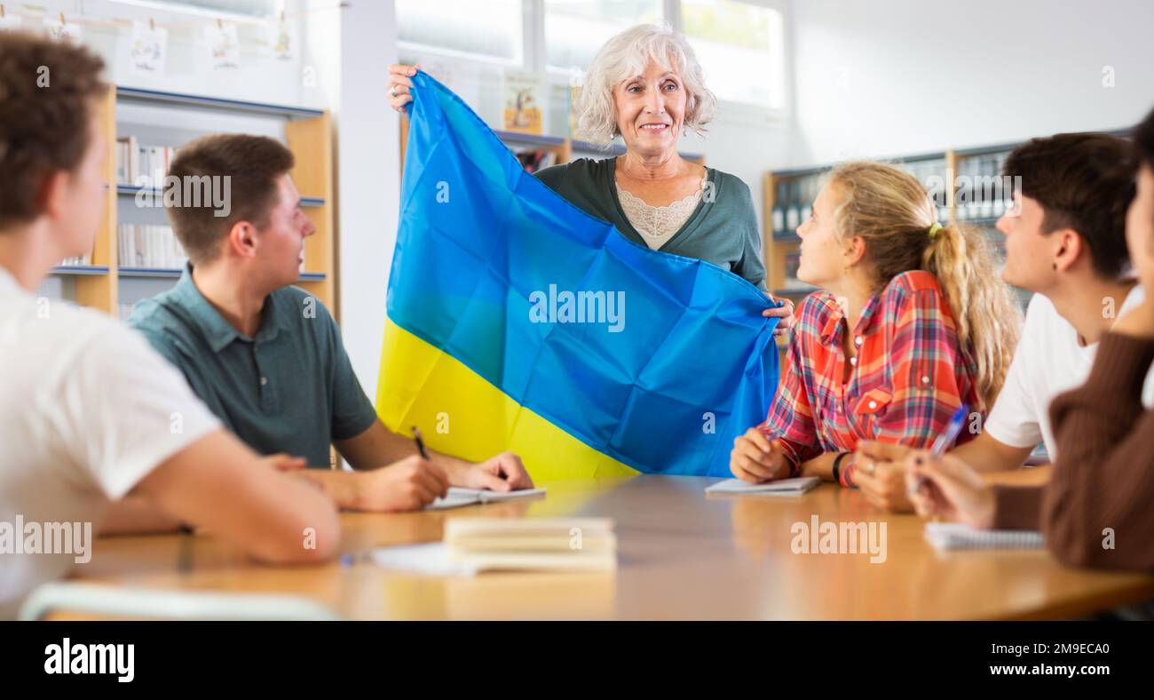 Mature female teacher working with schoolgirls and schoolboys, holding ...