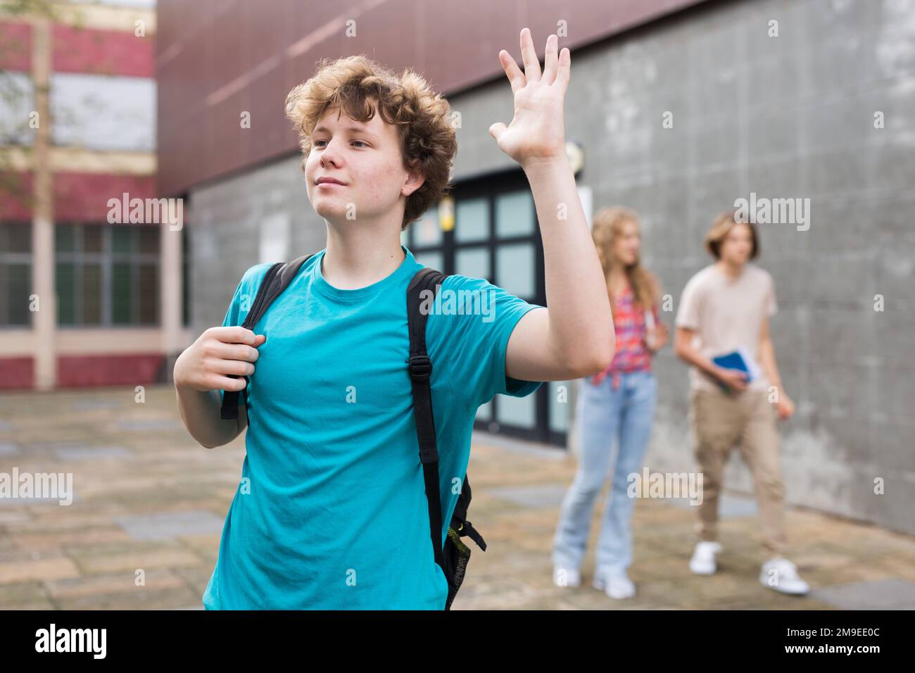 Teenager boy waving with hand beside school building Stock Photo - Alamy