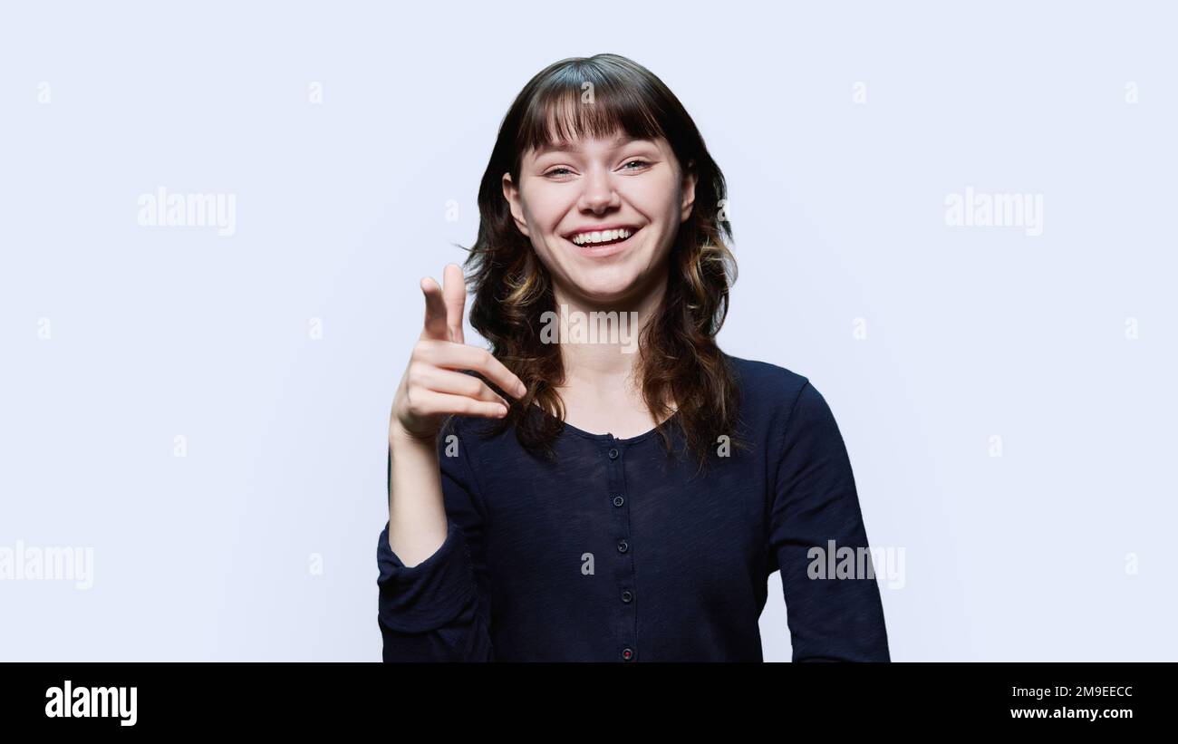 Laughing young female pointing finger at camera at you, white ...