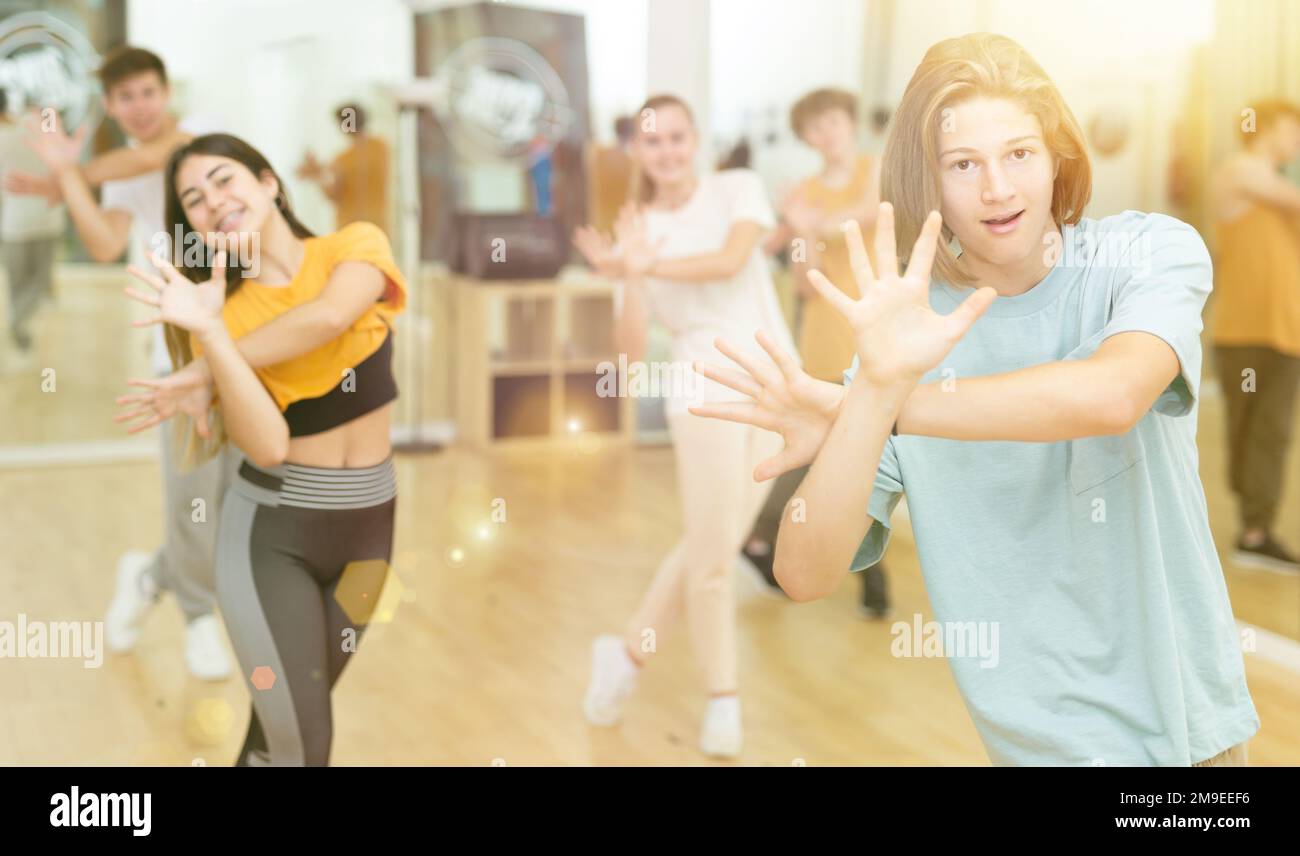 Smiling teenage boy practicing active dance with group in studio Stock ...