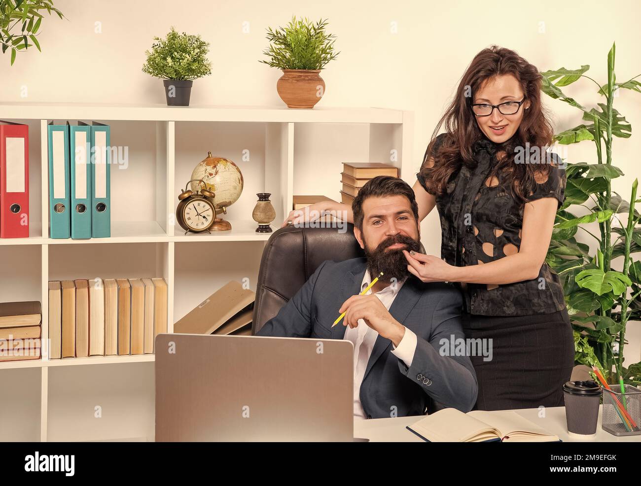 Ambitious girl touching man by beard at workplace in office, flirting ...