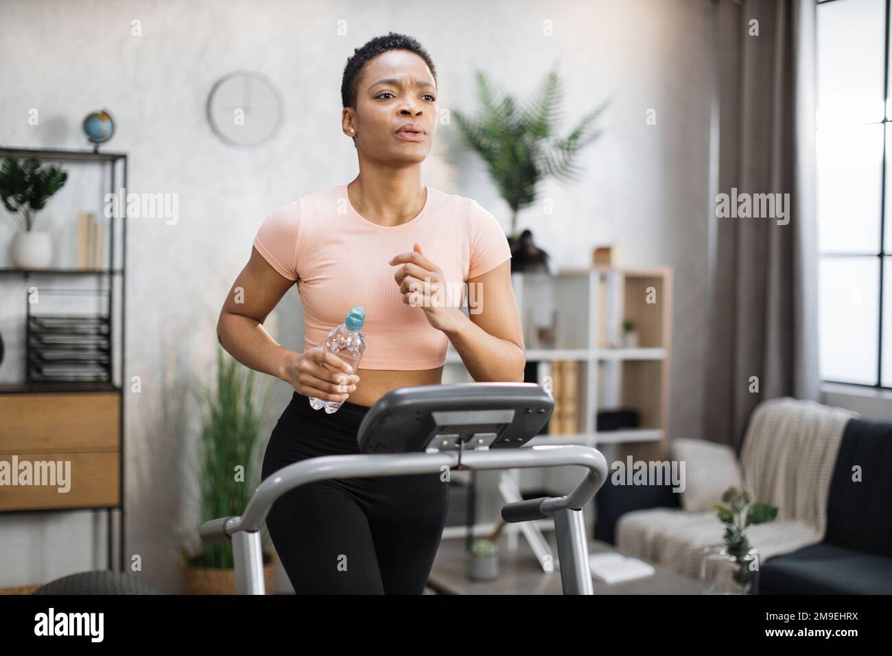 Attractive young sports african american woman holding bottle with ...