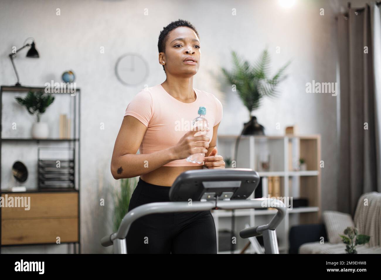 Attractive young sports african american woman holding bottle with ...