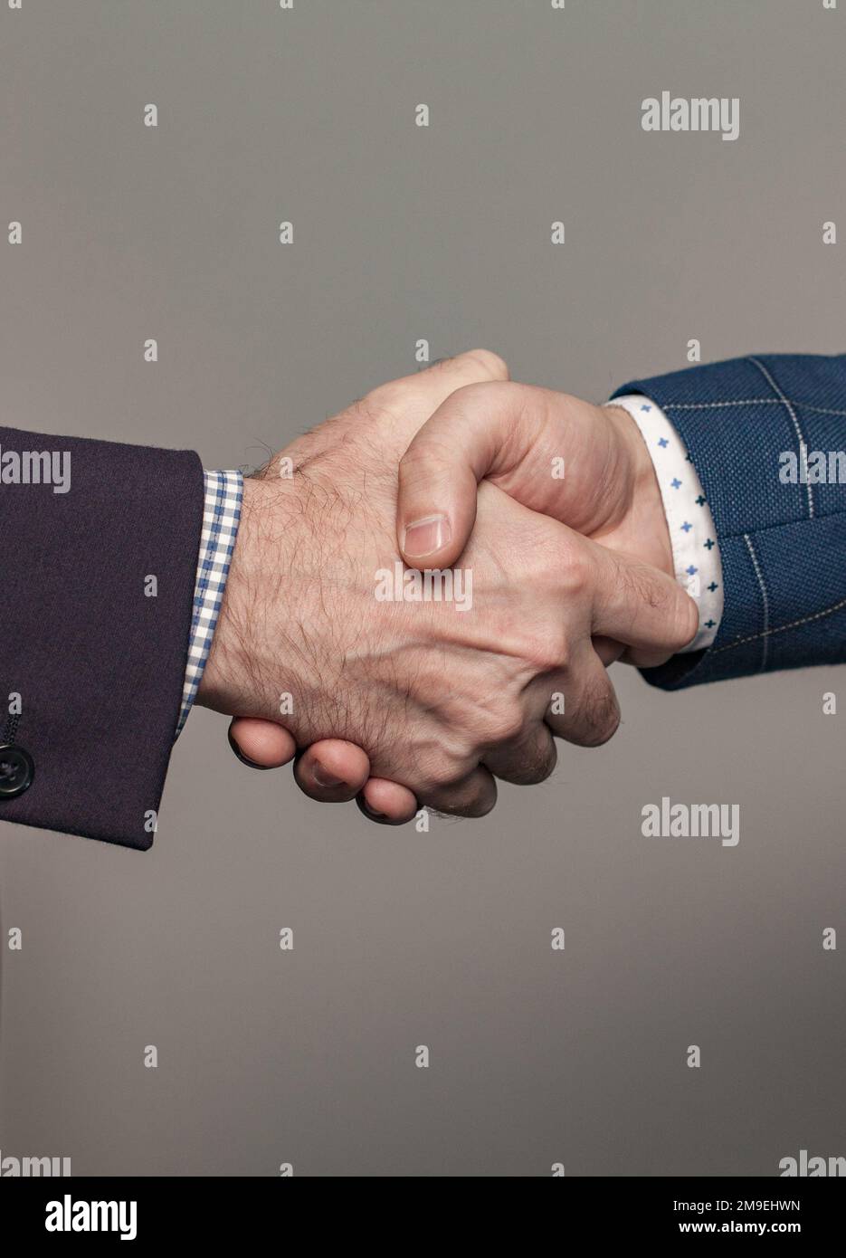 Business people in suit shaking hands, get an agreement, against grey ...