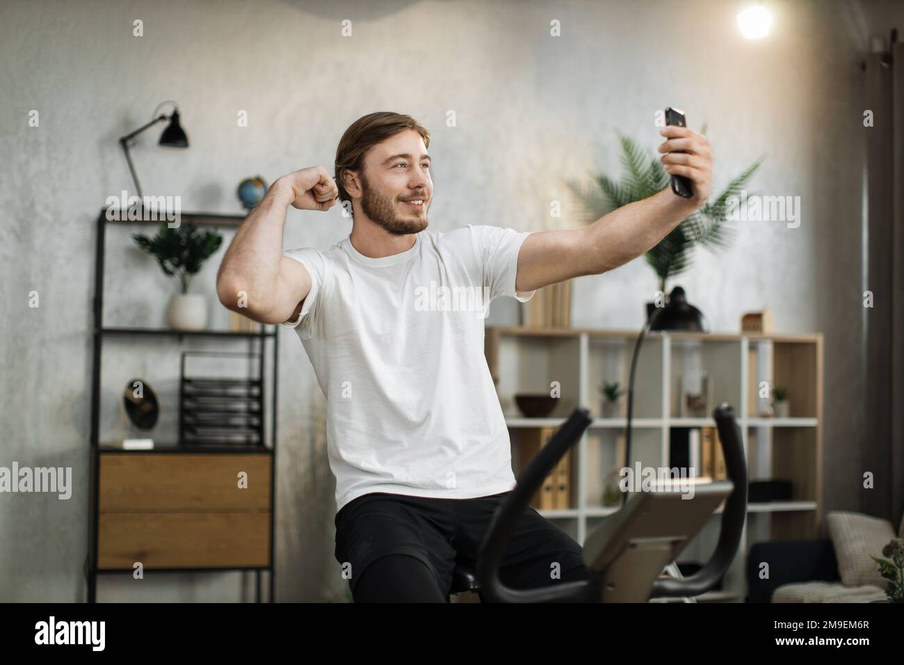 Focused young male wearing sportswear doing selfie, showing biceps ...