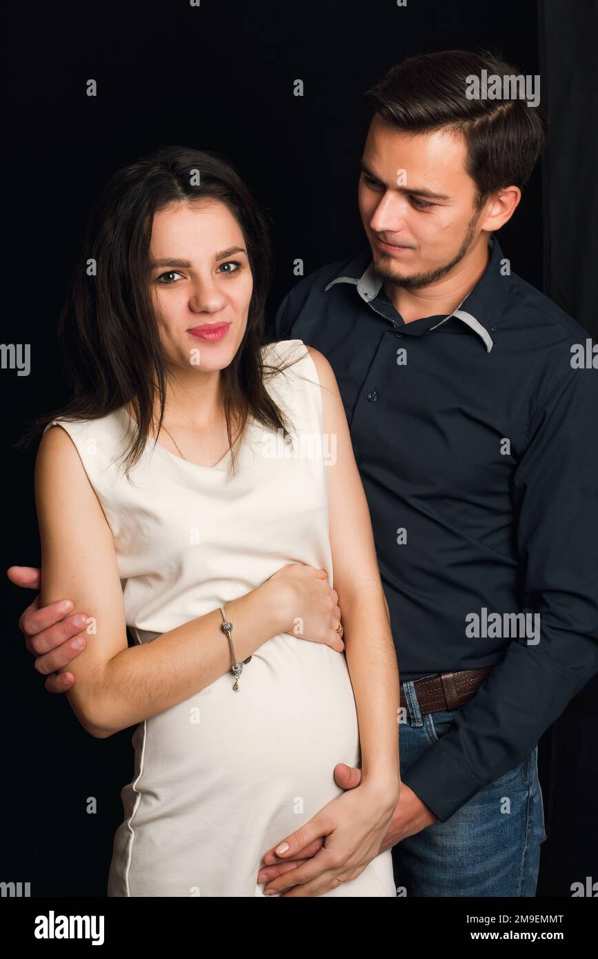 Happy Pregnant Wife And Husband Hugging On Black Background The