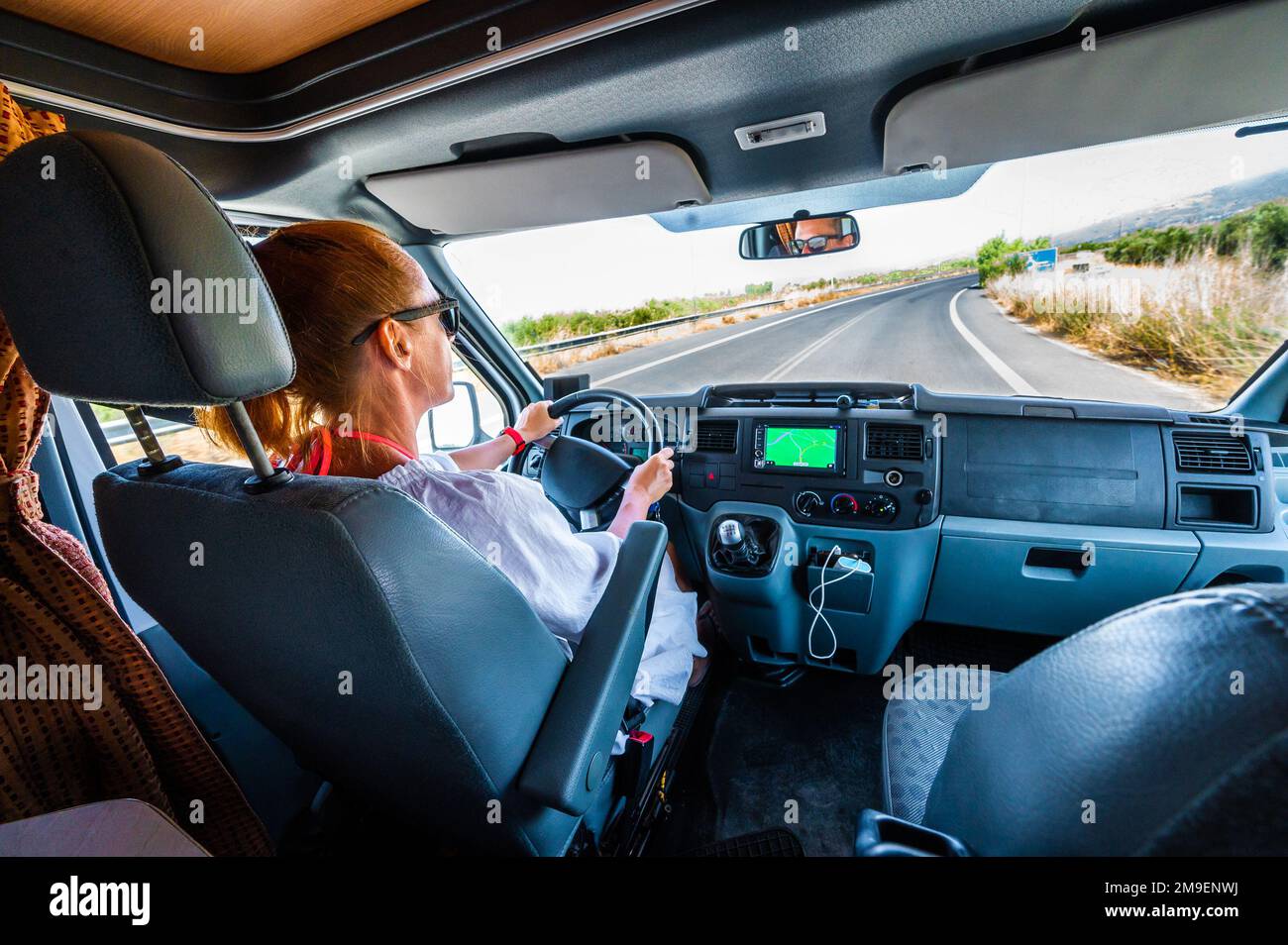 Woman is driving motorhome or campervan on the road outdoors in nature ...