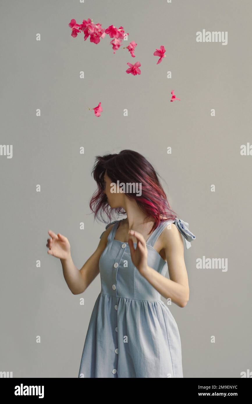 Close up lady shaking head with falling pink flowers from above ...