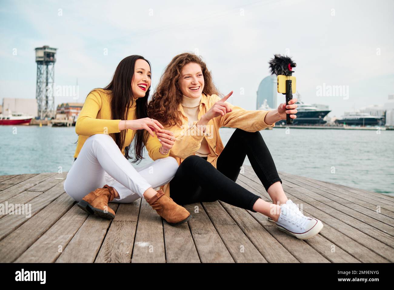 Two women smiling and having fun while streaming live with a mobile ...