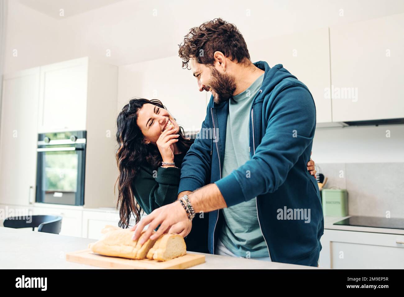 A young caucasian couple in their 30s shares a laugh while they eat ...
