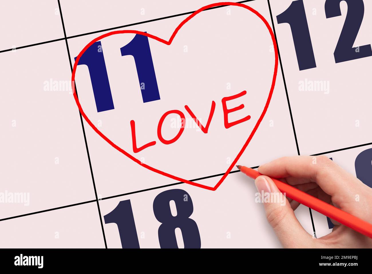 11th day of the month. Hand writing text LOVE and drawing a red heart ...