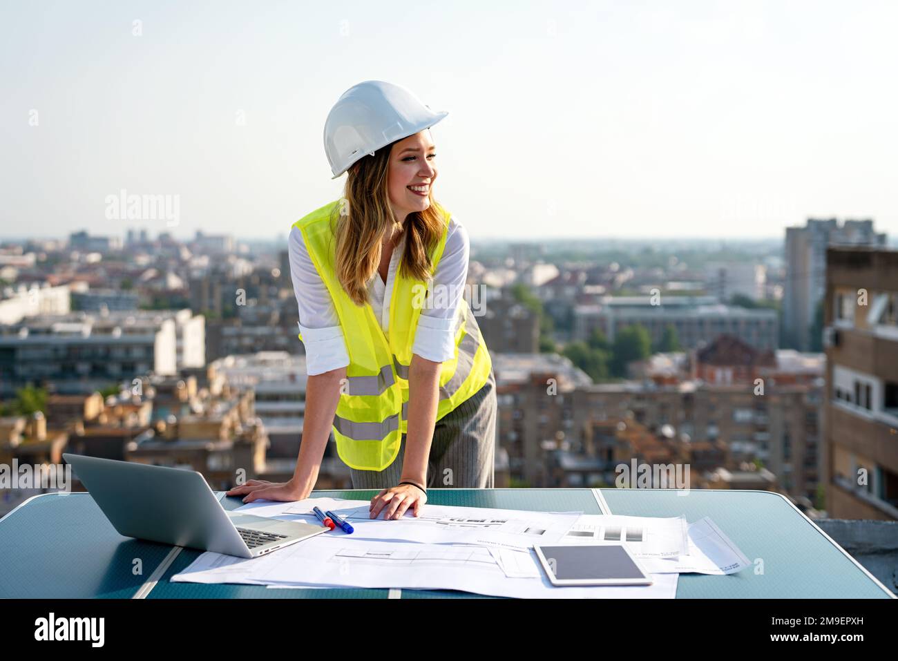 Young female construction specialist engineer reviewing blueprints at ...