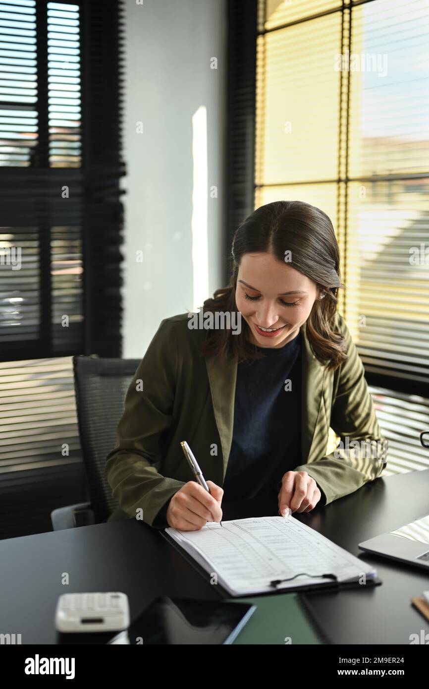Smiling caucasian female investor signing on business document at her ...