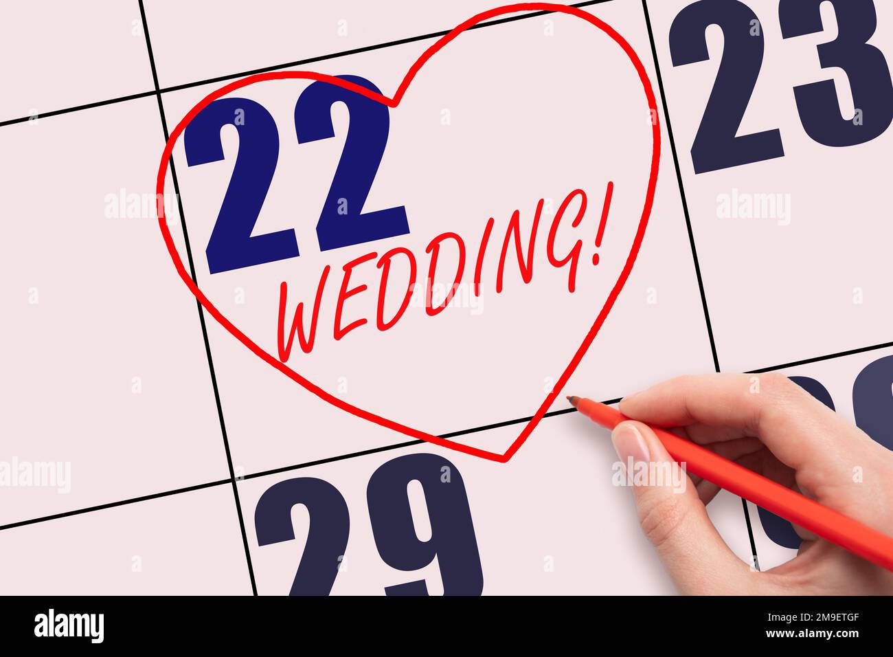 22nd day of the month. Hand writing text WEDDING and drawing a red ...