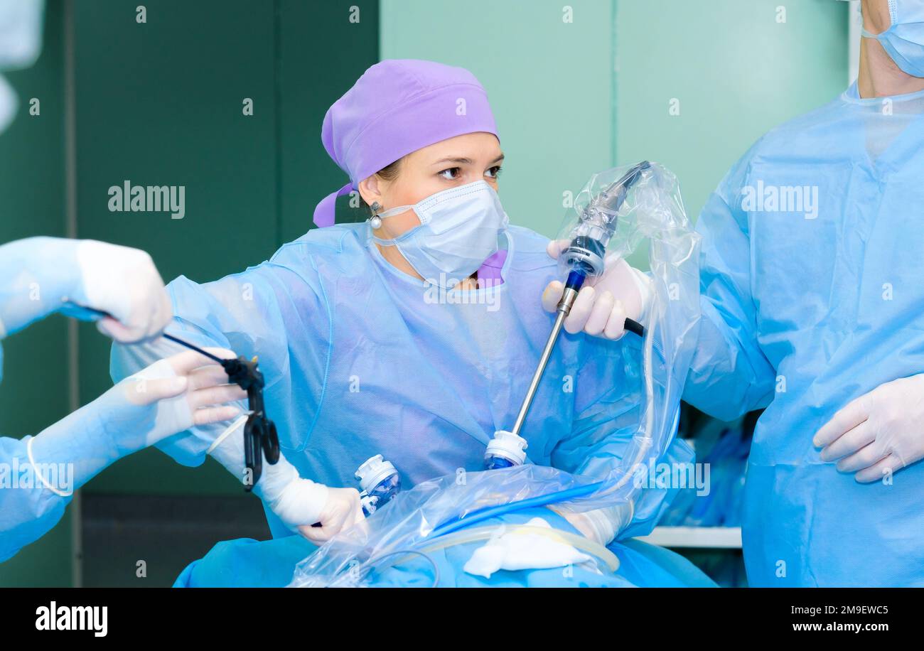 A female surgeon inserts a laparoscopic surgical instrument into the ...