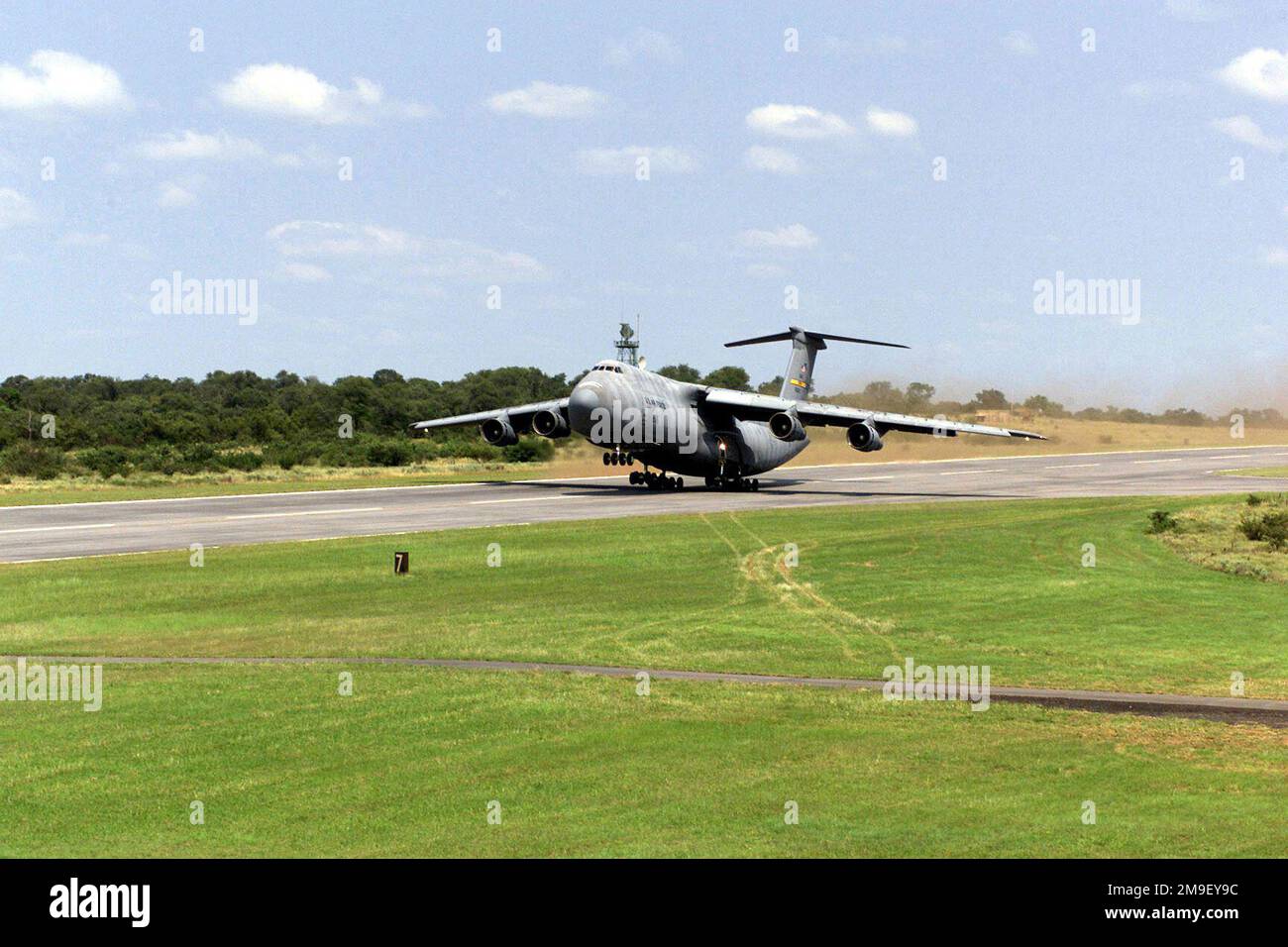 Extreme long shot. A heavily laden C-5 Galaxy begins to lift as it ...