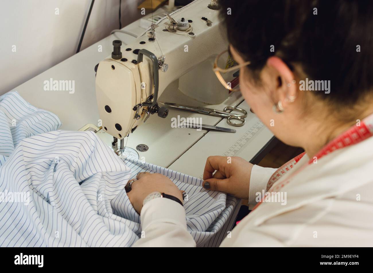 rear view of young caucasian seamstress woman working in her home ...