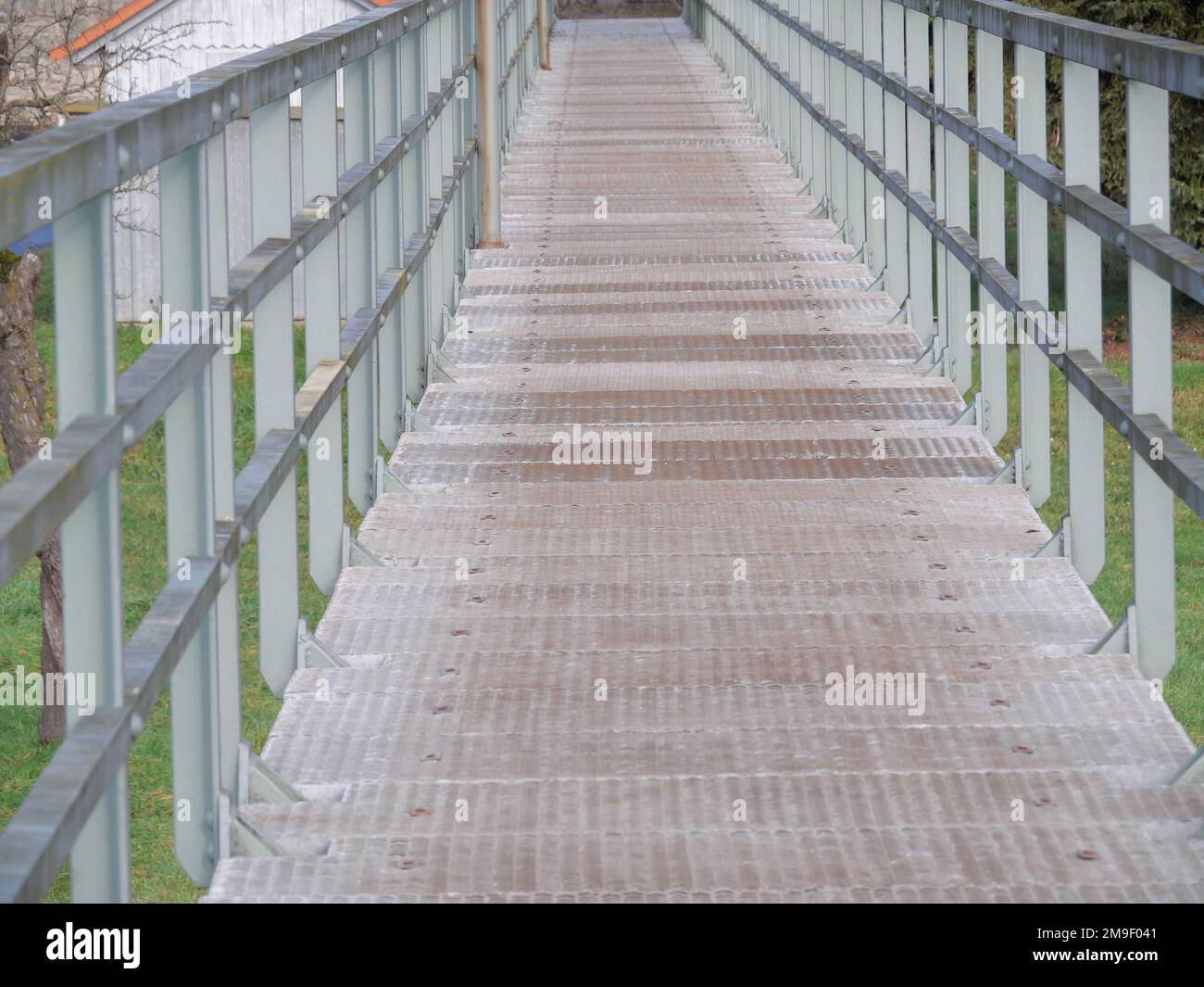 Perspective view of a pedestrian bridge with steel railing and grating ...