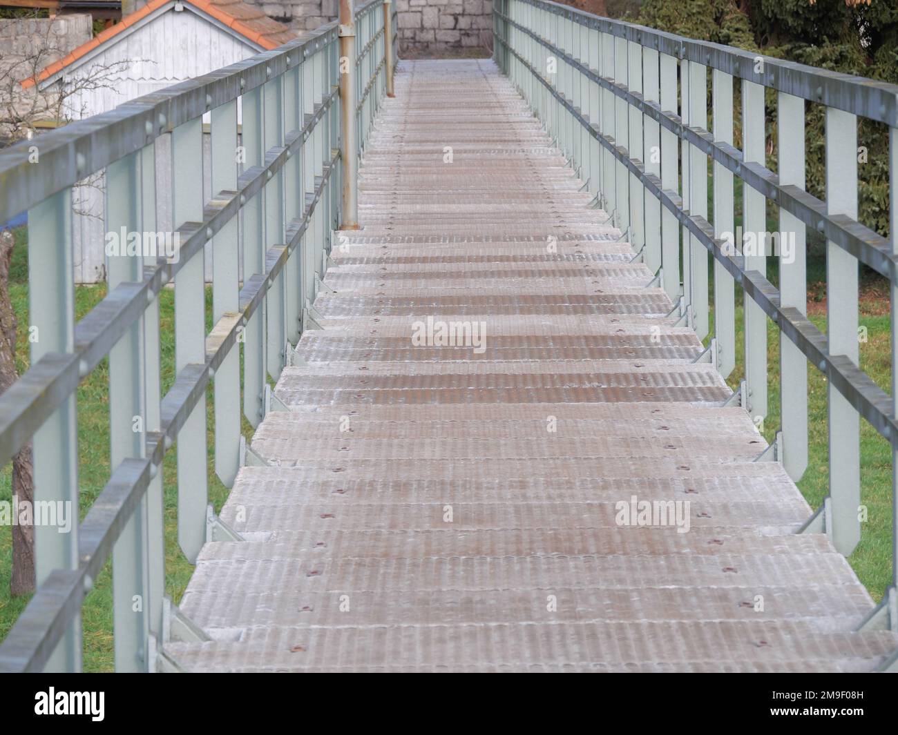 Perspective view of a pedestrian bridge with steel railing and grating ...