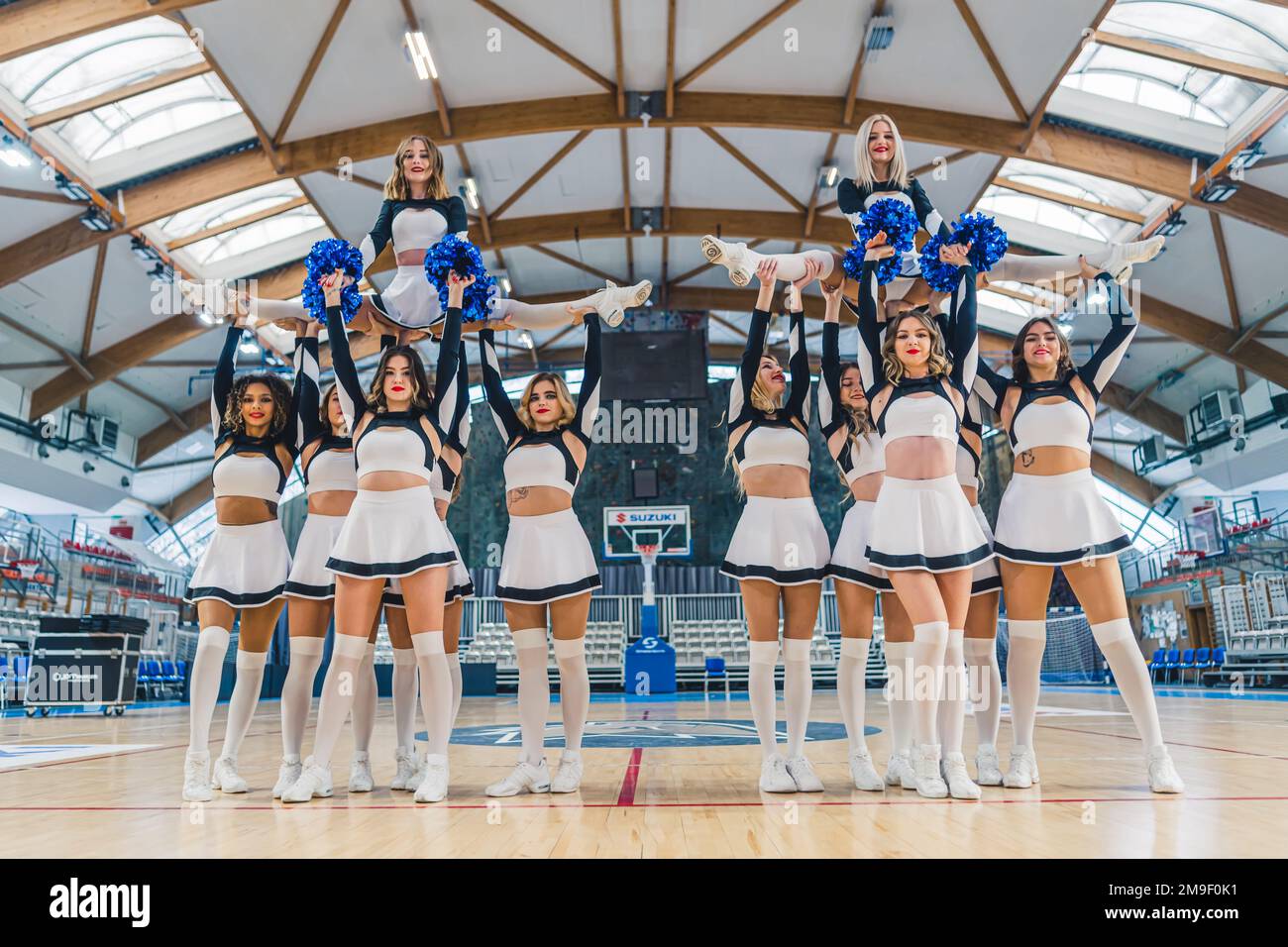 Cheerleading team posing in the basketball court. Two team members ...