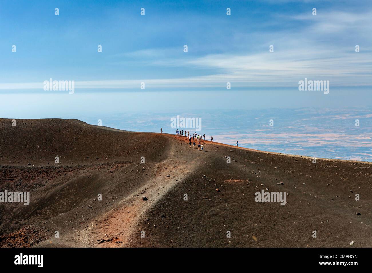 People walking along a ridge ascending to Mount Etna, Europe’s highest ...