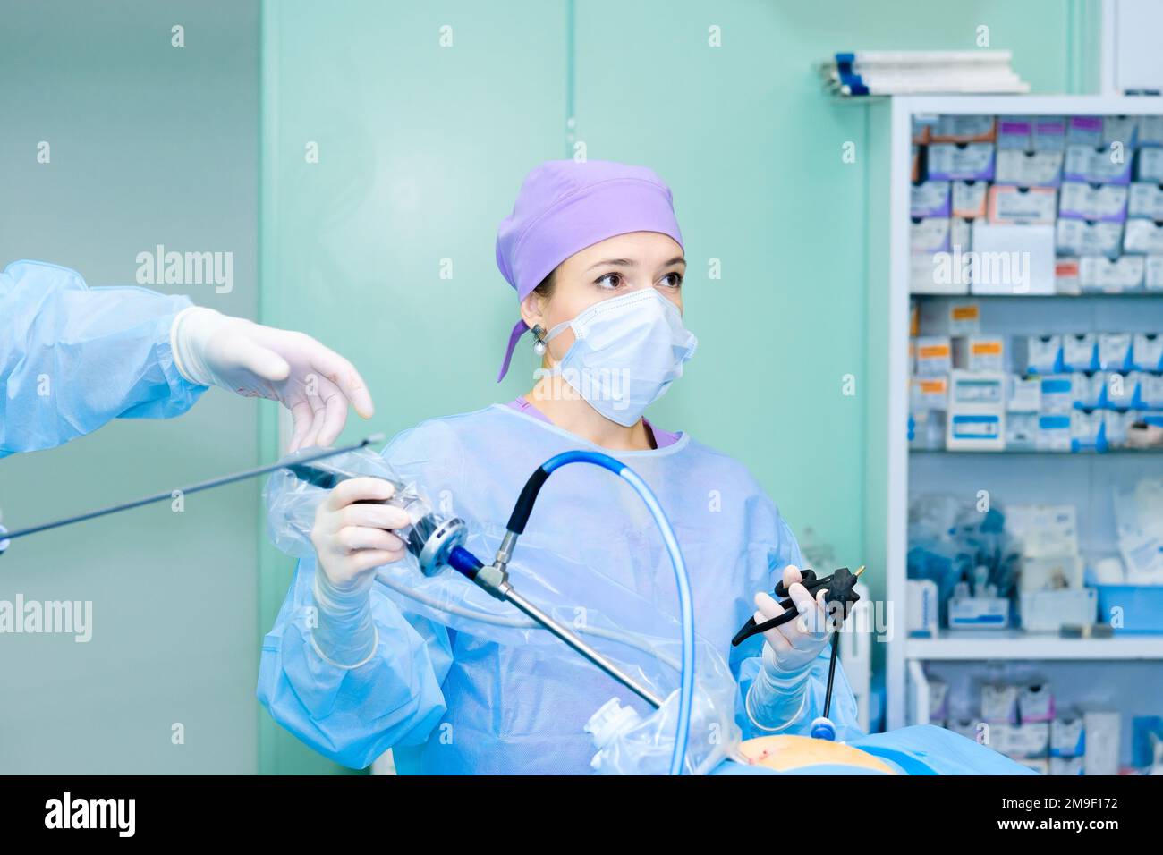Portrait of a pretty young female surgeon with surgical laparoscopic ...