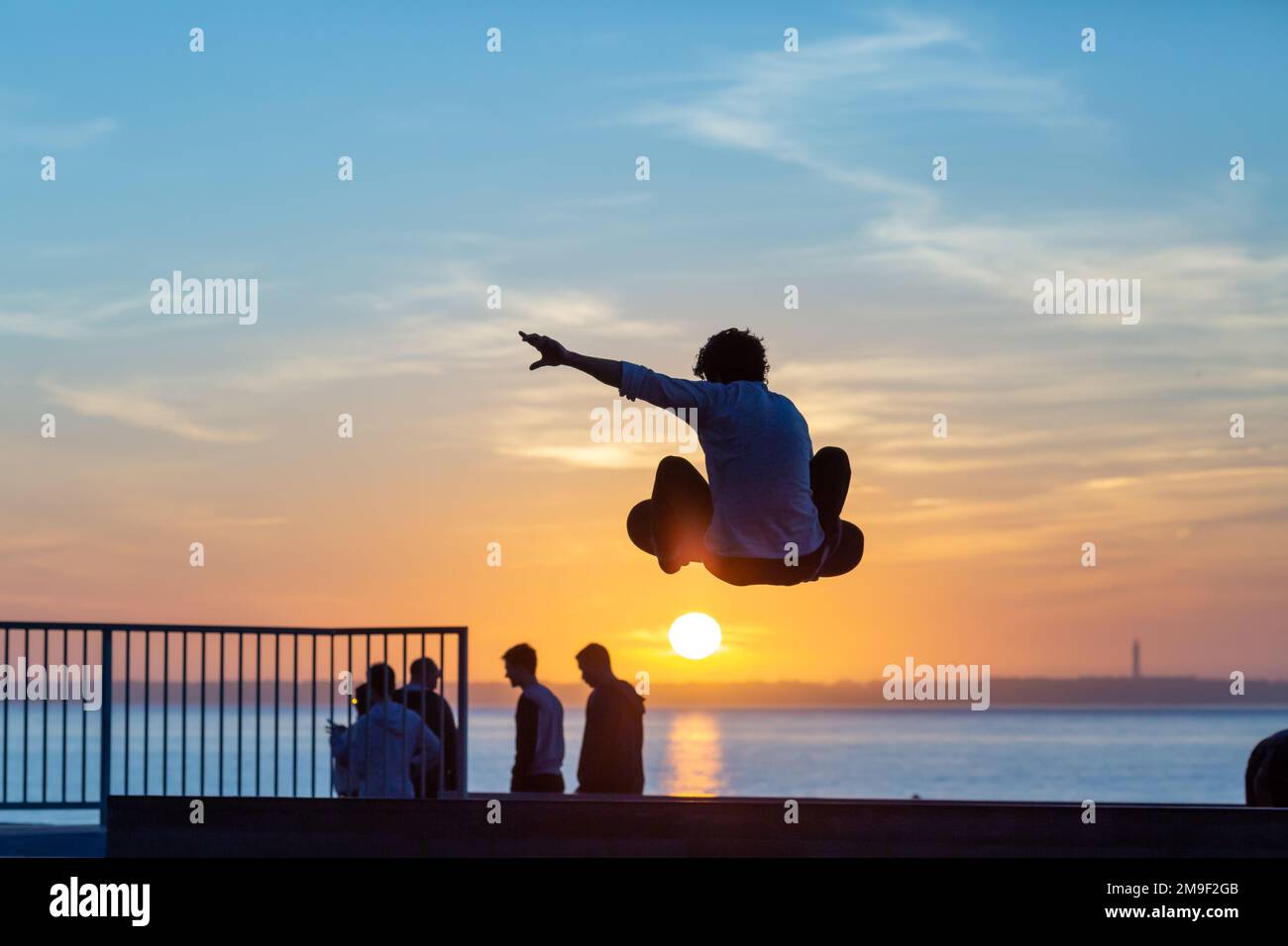 Unrecognizable teenage boy silhouette showing high jump tricks on ...