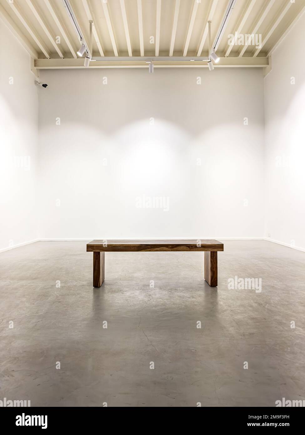 An empty wooden bench looking out on empty wall of a Mumbai art gallery ...