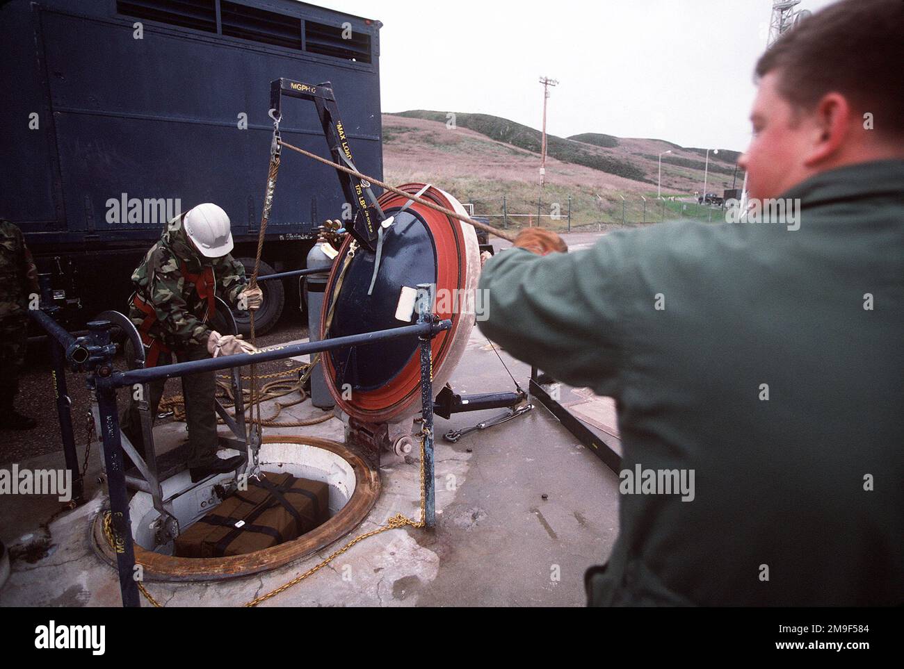 US Air Force maintenance personnel use a hoist to lower one of the 13 ...