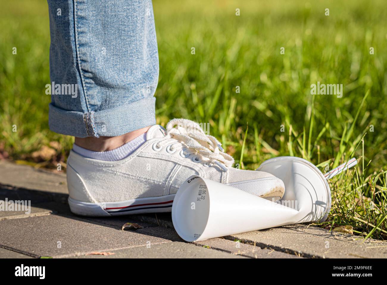 leg crushes a paper cup lying on the ground. man stepped on a ...