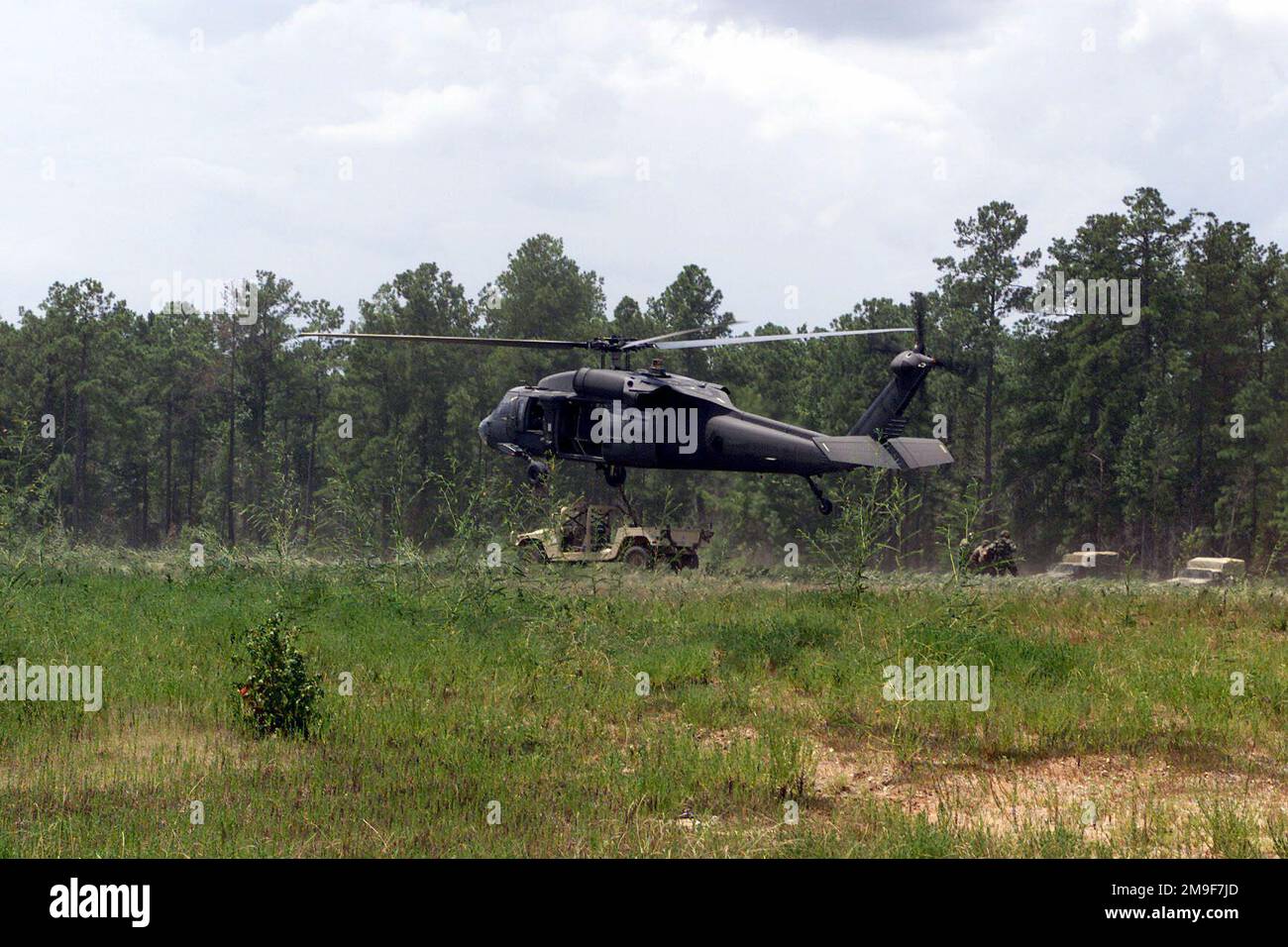 A UH-60 Blackhawk helicopter prepares to lift off with a High-Mobility ...
