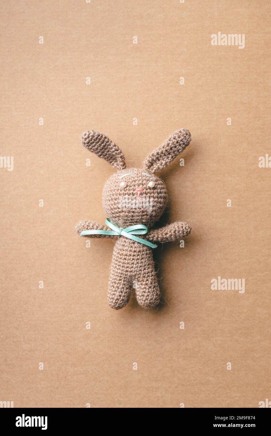 Cute crocheted baby toy bunny on beige background. Knitted rabbit top ...