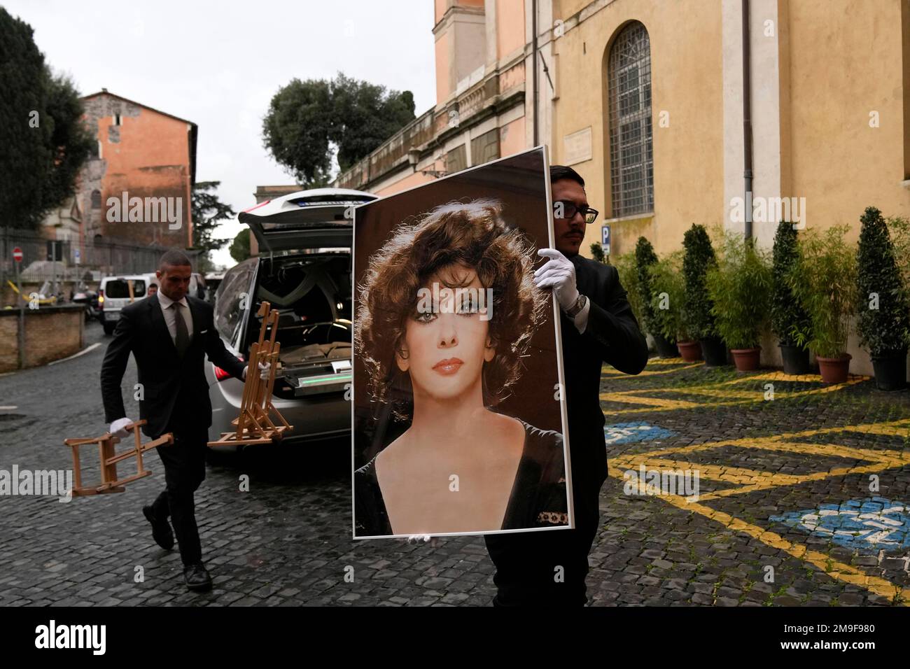 A funeral service employee carries a photo of late Italian film legend ...