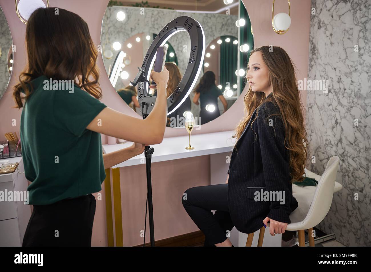 Makeup artist photographing client in beauty salon. Young woman with ...