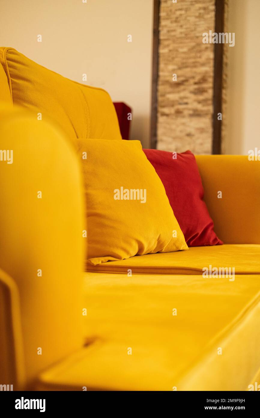 A vertical shot of a yellow modern couch in the living room of the ...