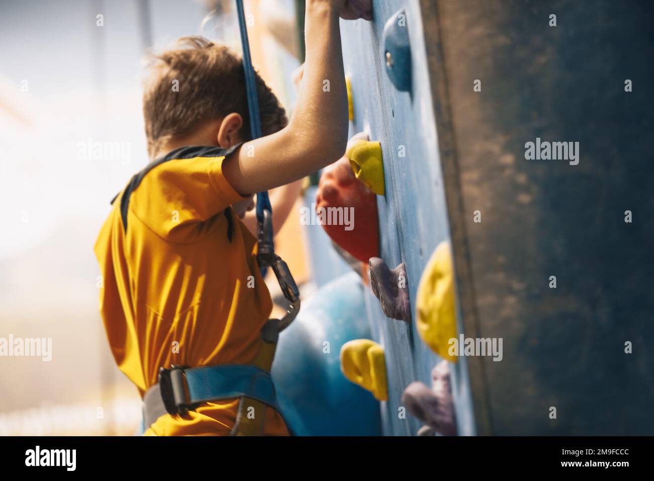 Little boy climbing a rock wall indoor. Bouldering training class for ...